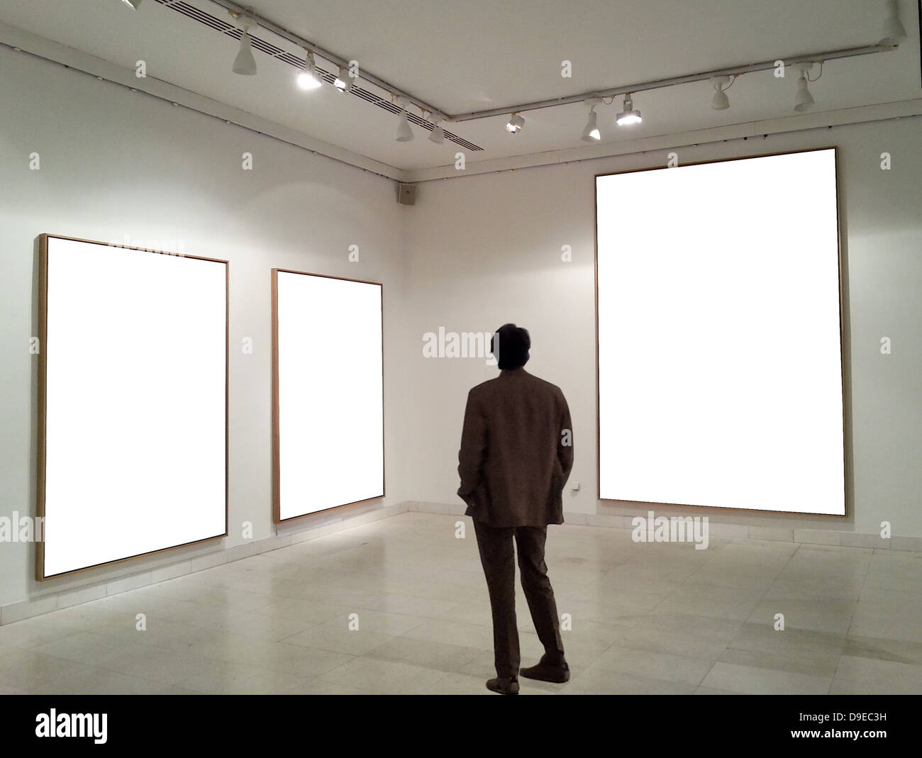 Man in gallery room looking at empty frames Stock Photo - Alamy