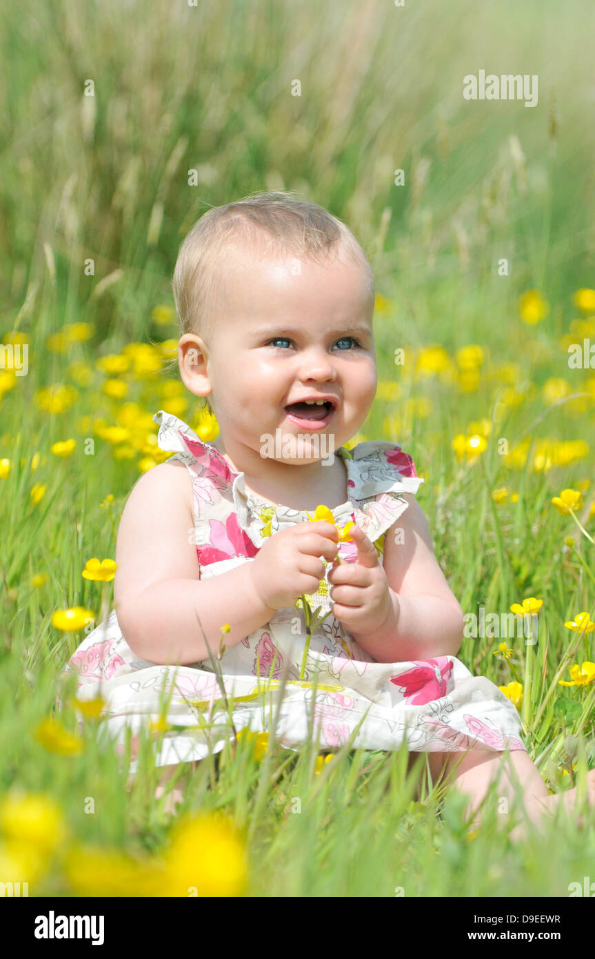 Baby sitting in field of buttercups Stock Photo - Alamy