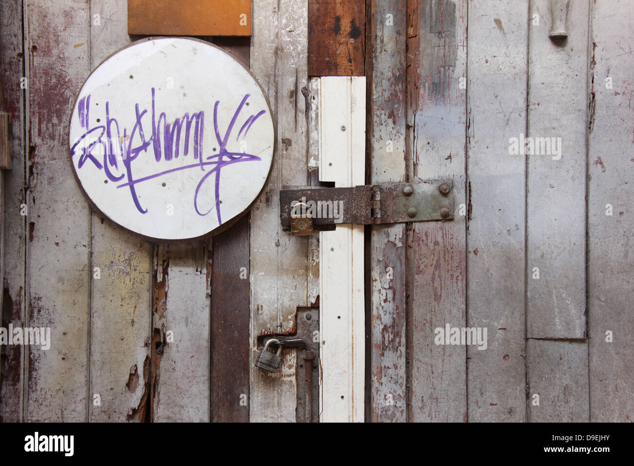 Wooden door locked with a strange graffiti sign Stock Photo - Alamy