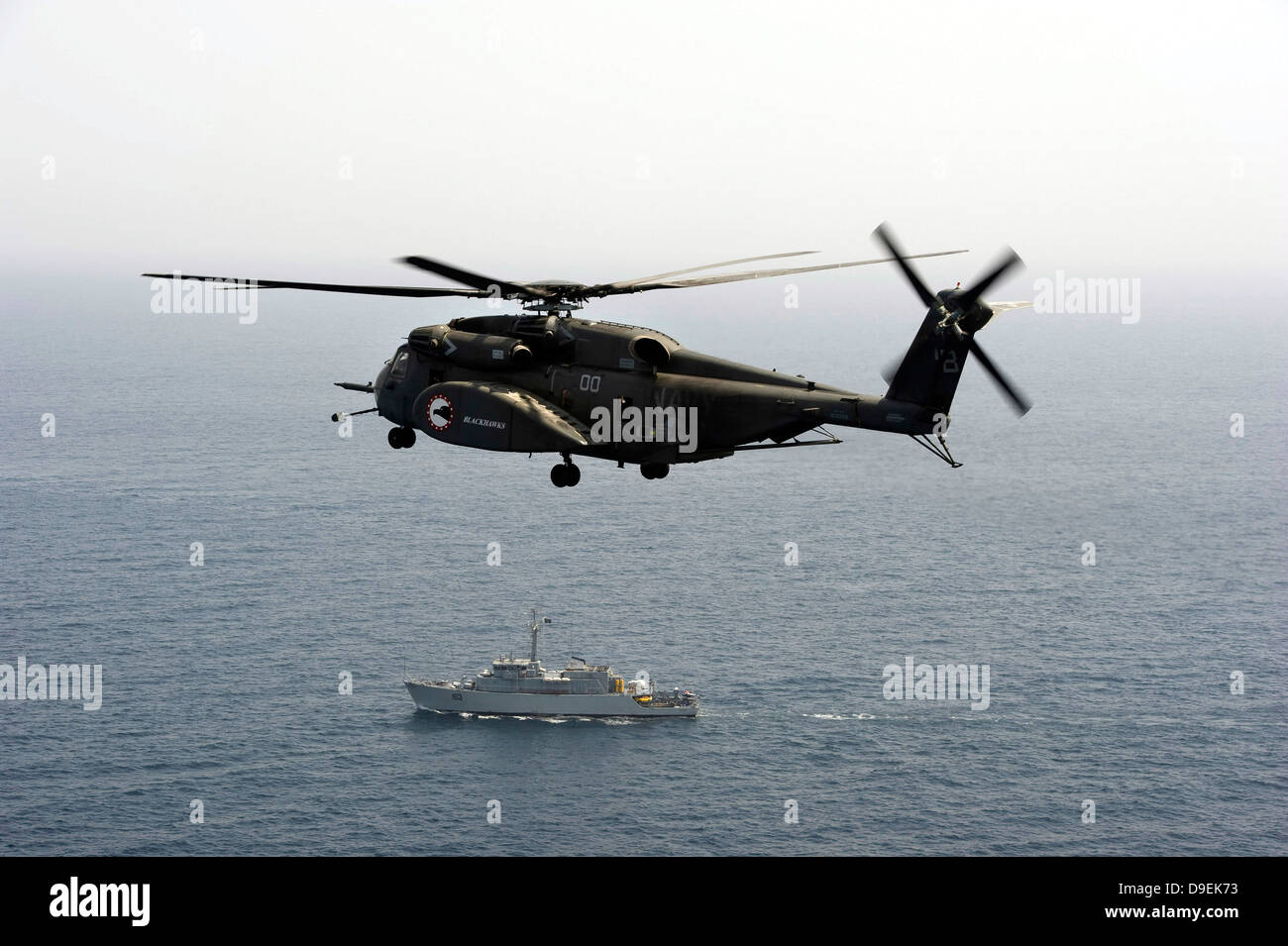 A CH-53 Sea Stallion flies above the mine countermeasures ship USS ...