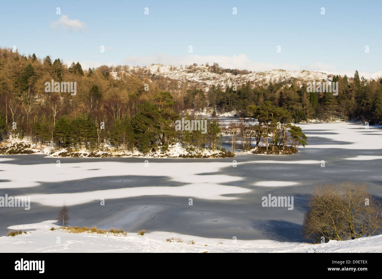 Tarn Hows covered with ice and surrounding hills are covered with snow ...