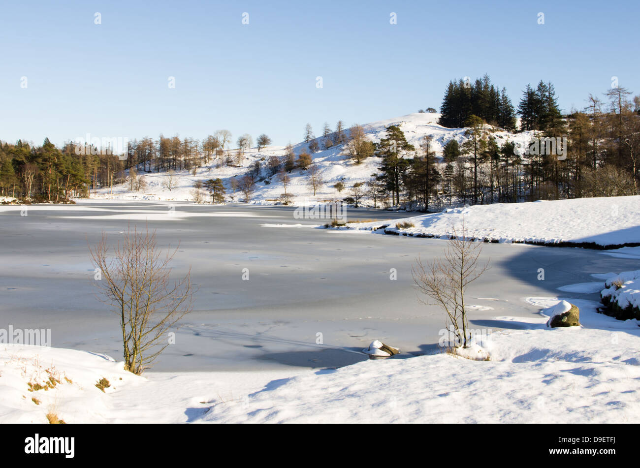 Tarn Hows covered with ice and surrounding hills are covered with snow ...