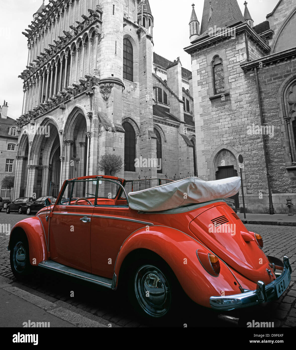 A bright orange, open top VW Beetle car, with the top down, parked near ...