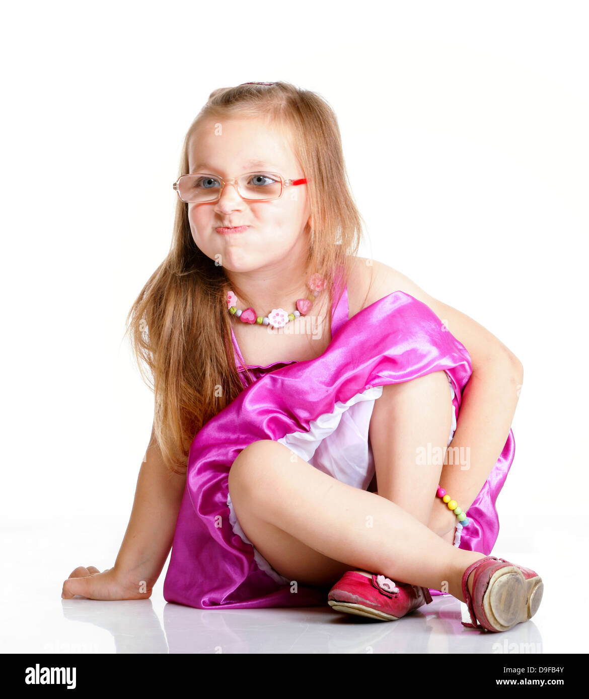 Full lehgth a cute girl sitting on floor puffs up her cheeks on white ...