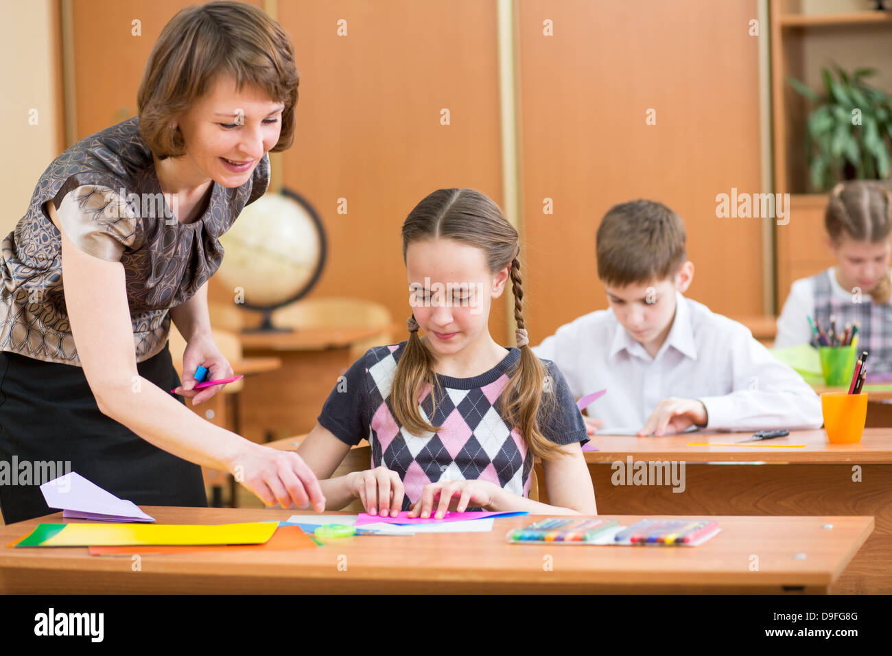 School kids work at labour lesson. Teacher looking at pupil Stock Photo ...