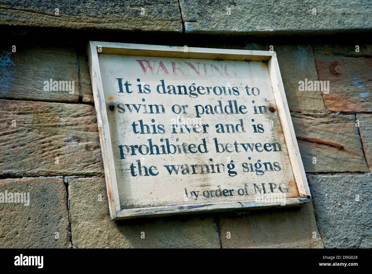 Danger warning sign attached to a wall about swimming or paddling in ...