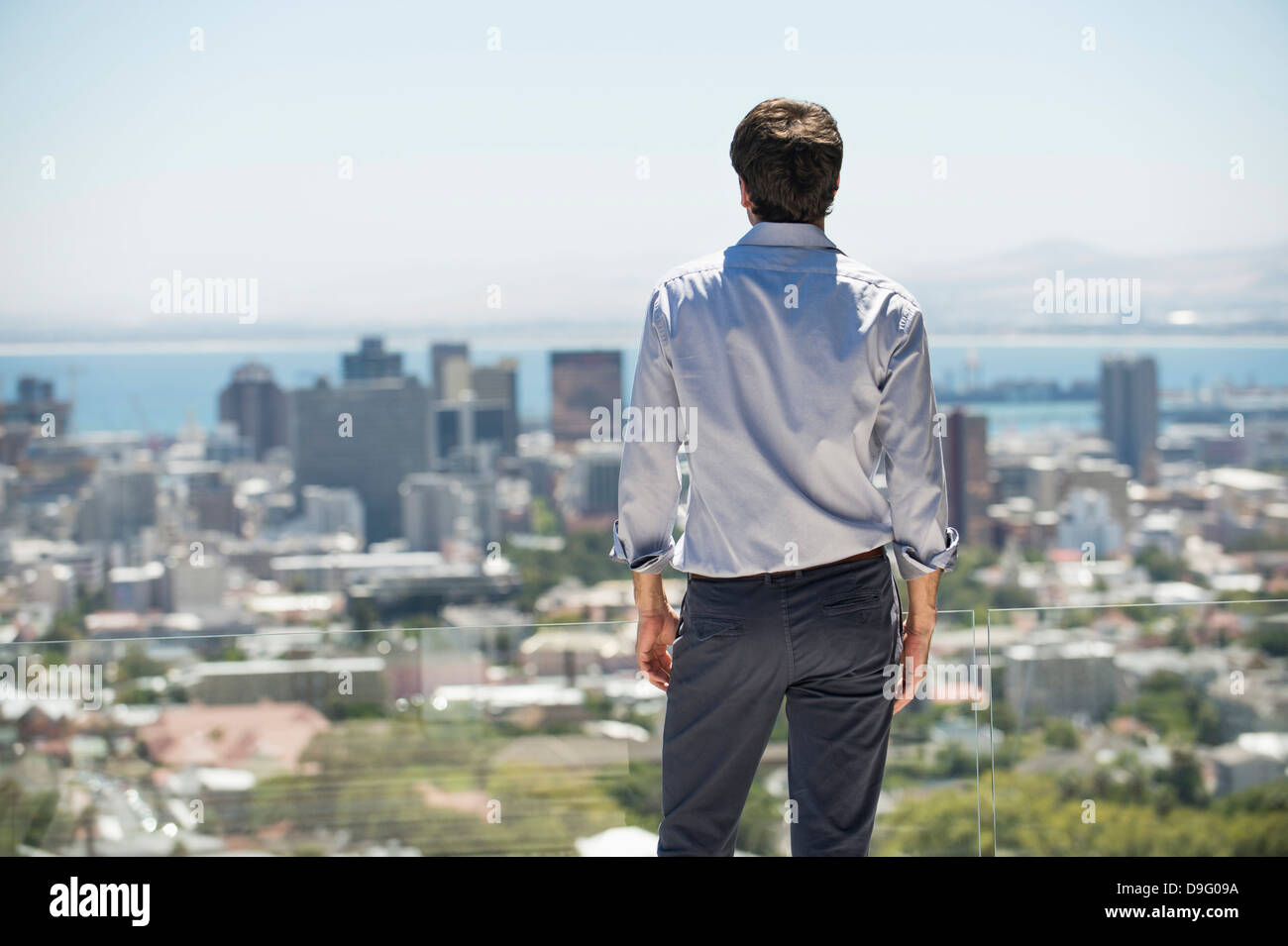 Man standing on the terrace looking at a city Stock Photo - Alamy