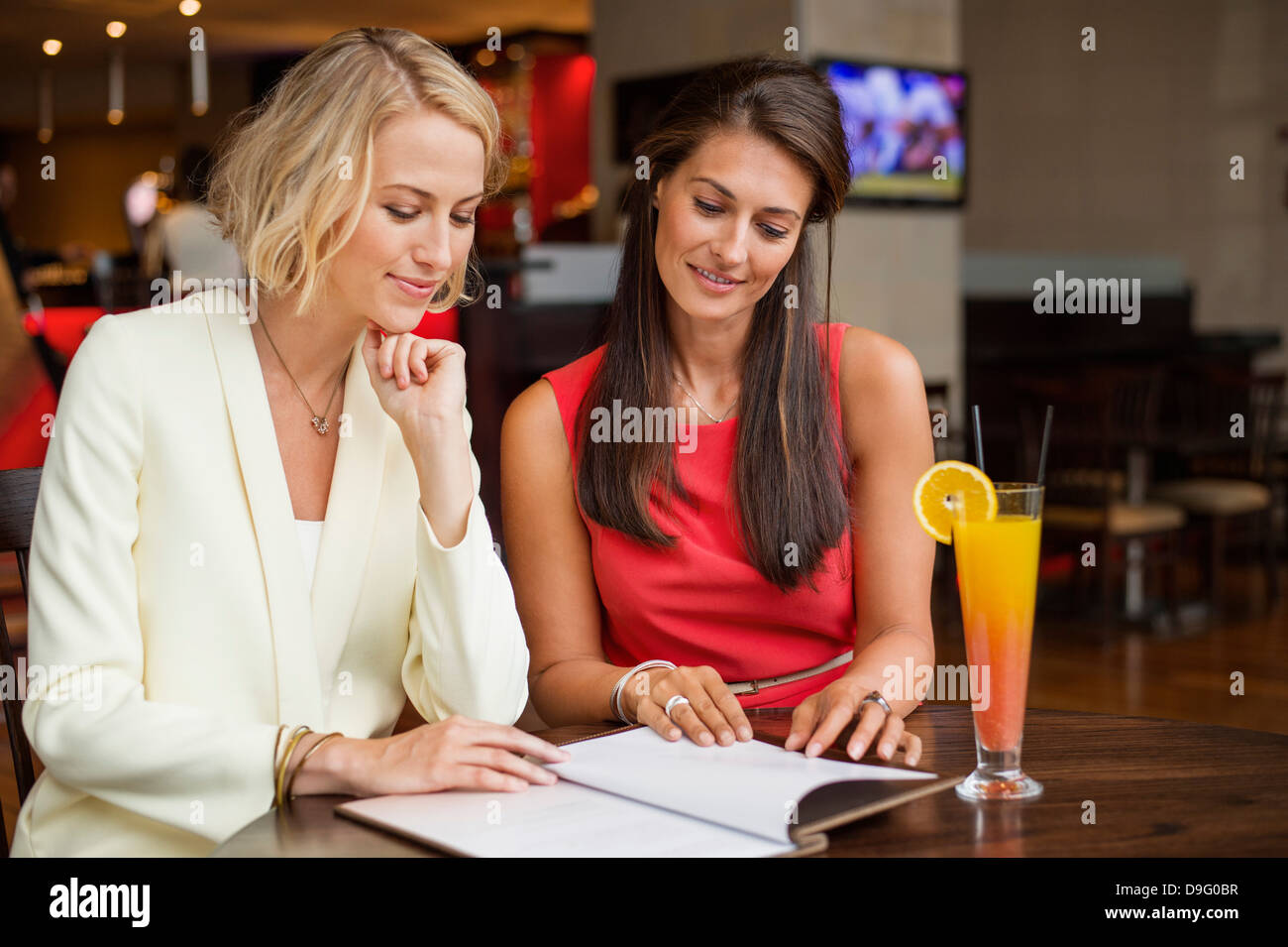 Two female friends looking at menu in a restaurant Stock Photo - Alamy