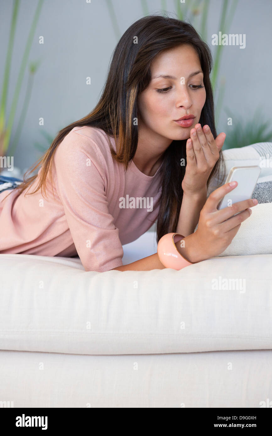 Woman reading text message on a mobile phone and giving flying kiss ...