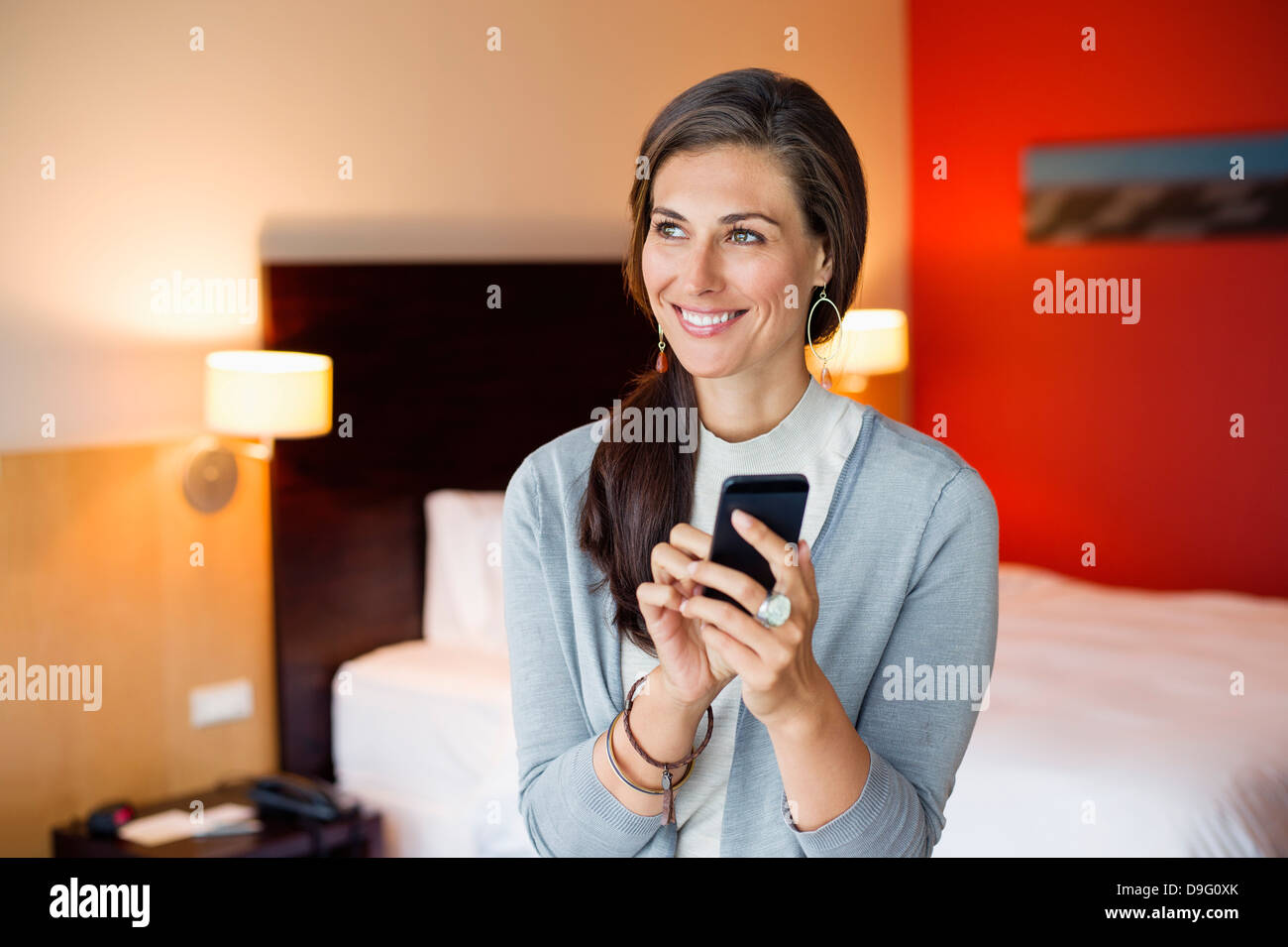 Woman using a cell phone in a hotel room Stock Photo - Alamy