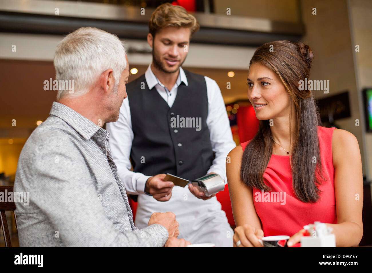 Couple paying with a credit card to a waiter in a restaurant Stock ...