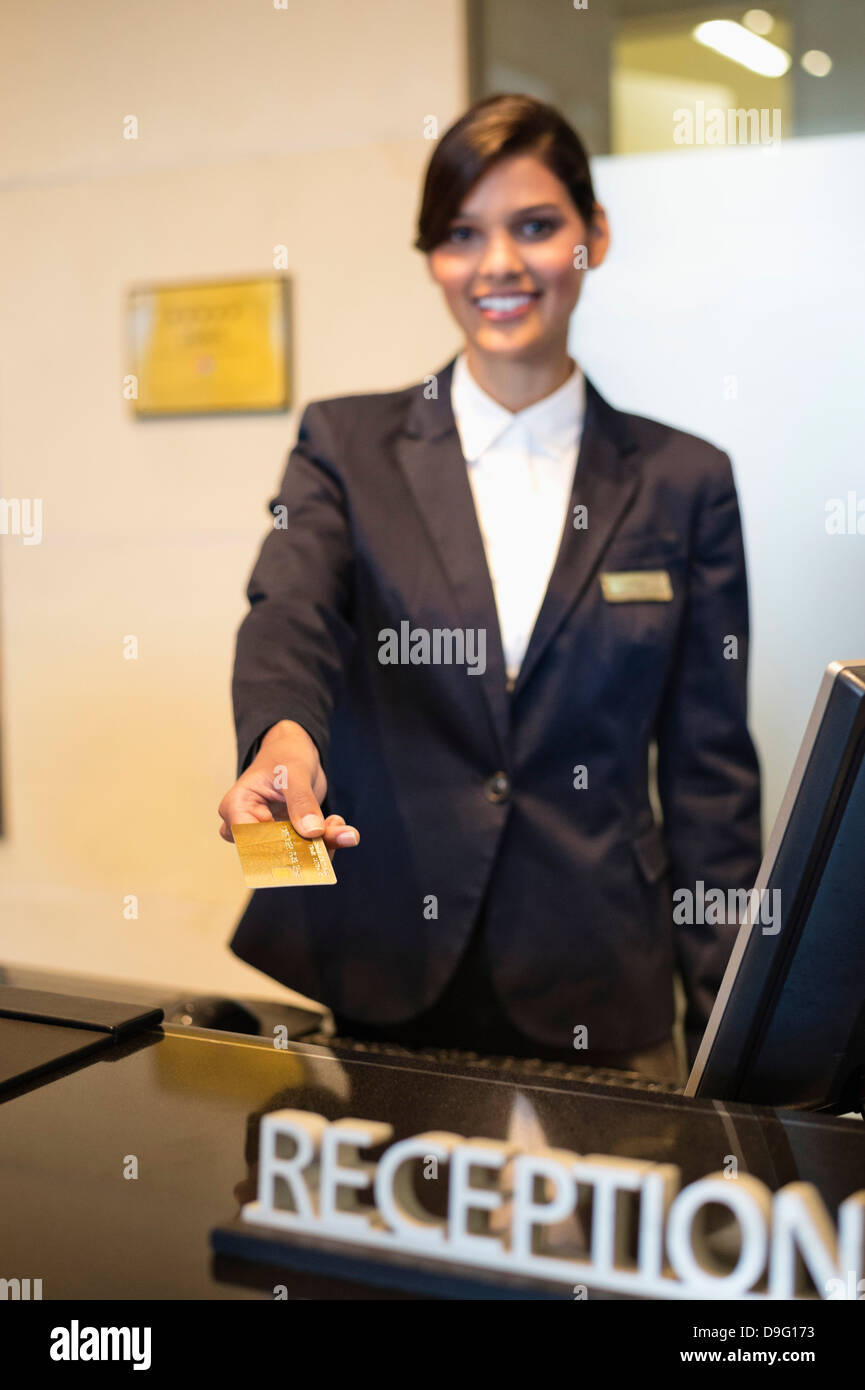 Receptionist holding a credit card and smiling at the hotel reception ...
