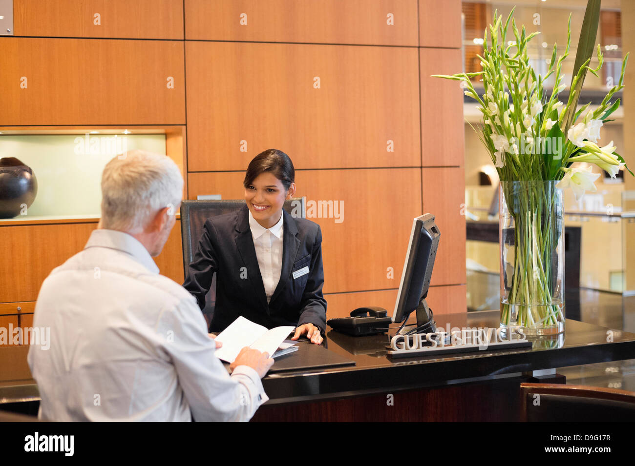 Businessman talking with a receptionist at the hotel reception counter ...