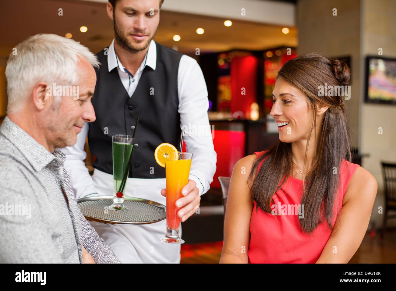 Waiter serving drinks to a couple in a restaurant Stock Photo - Alamy