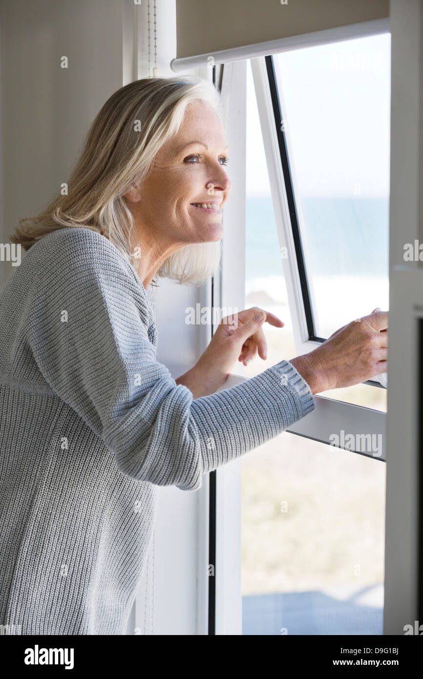 Woman looking through a window Stock Photo - Alamy