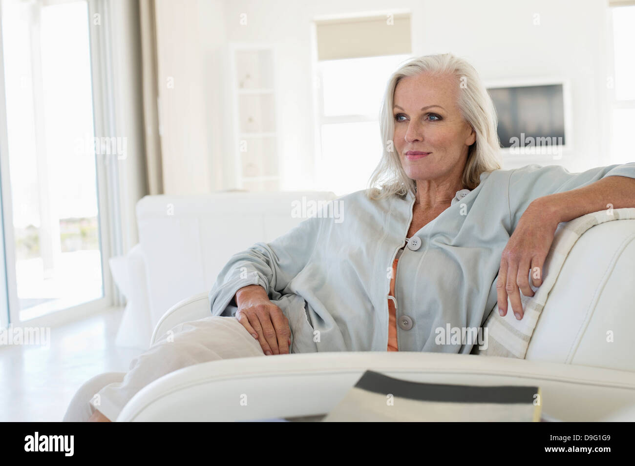 Woman sitting on a couch and thinking Stock Photo - Alamy