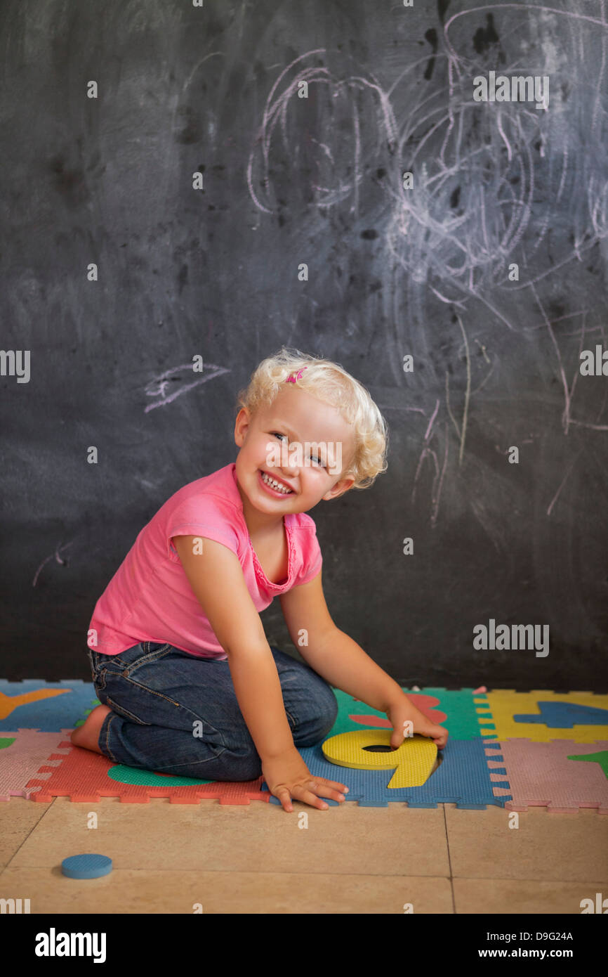 Smiling girl playing with number puzzle in front of a blackboard Stock ...