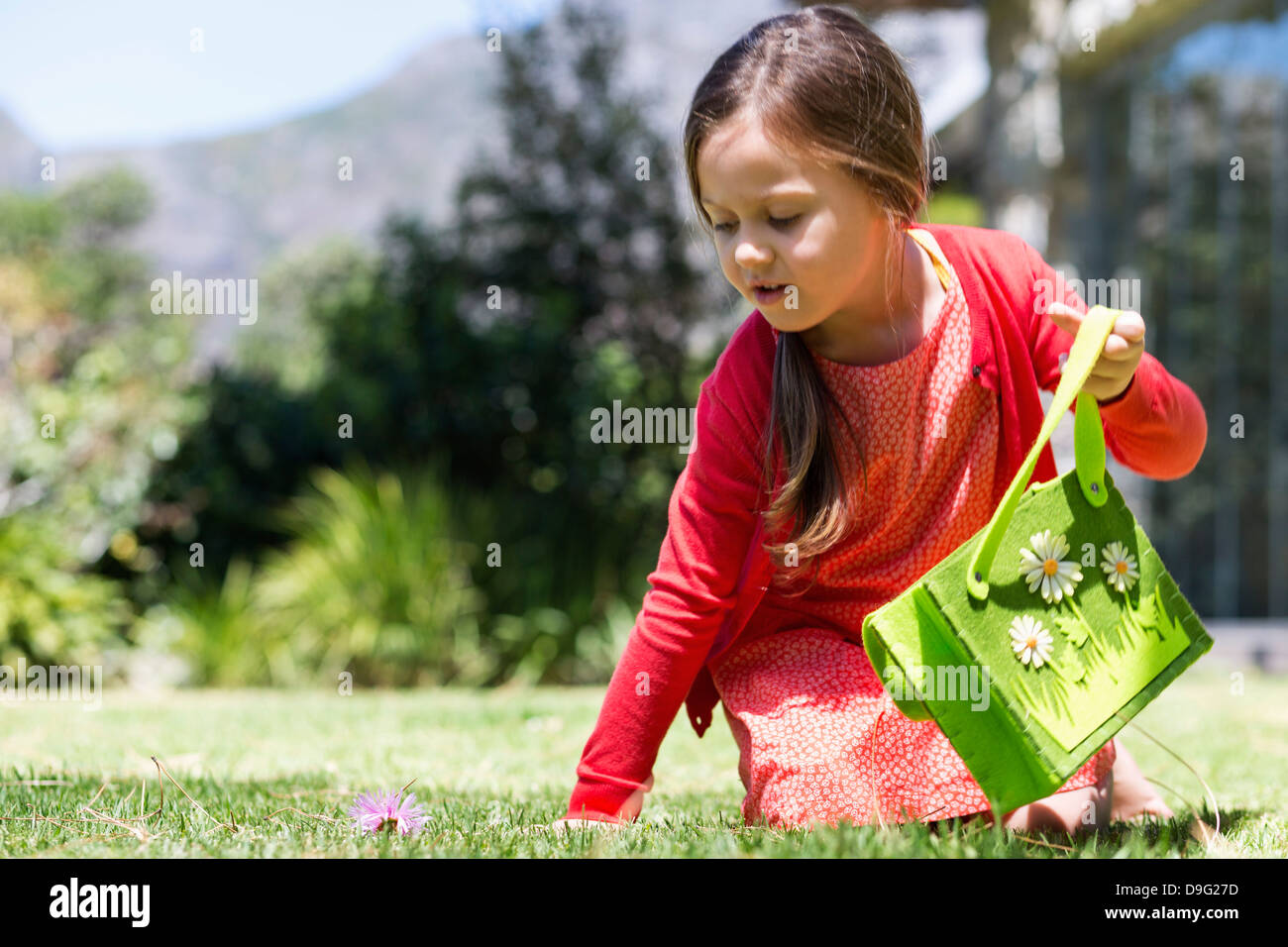 Girl looking at a flower in a lawn Stock Photo - Alamy