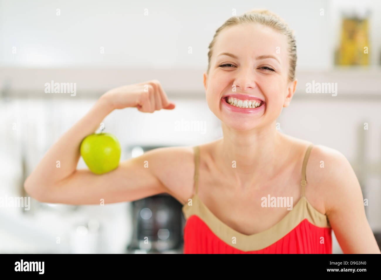 Happy teenage girl showing biceps and apple Stock Photo - Alamy