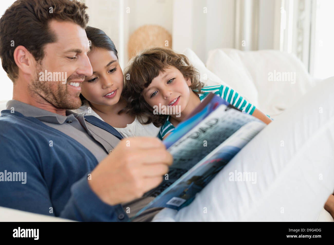 Man reading a magazine with his children Stock Photo - Alamy