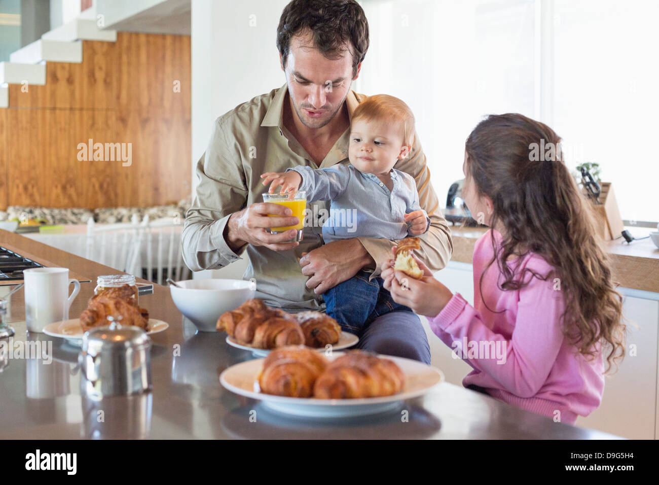 Family having breakfast at a kitchen counter Stock Photo - Alamy