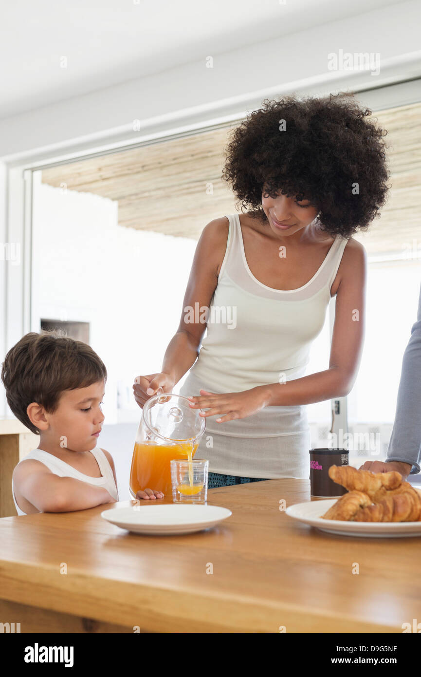 Woman giving orange juice to her son Stock Photo - Alamy