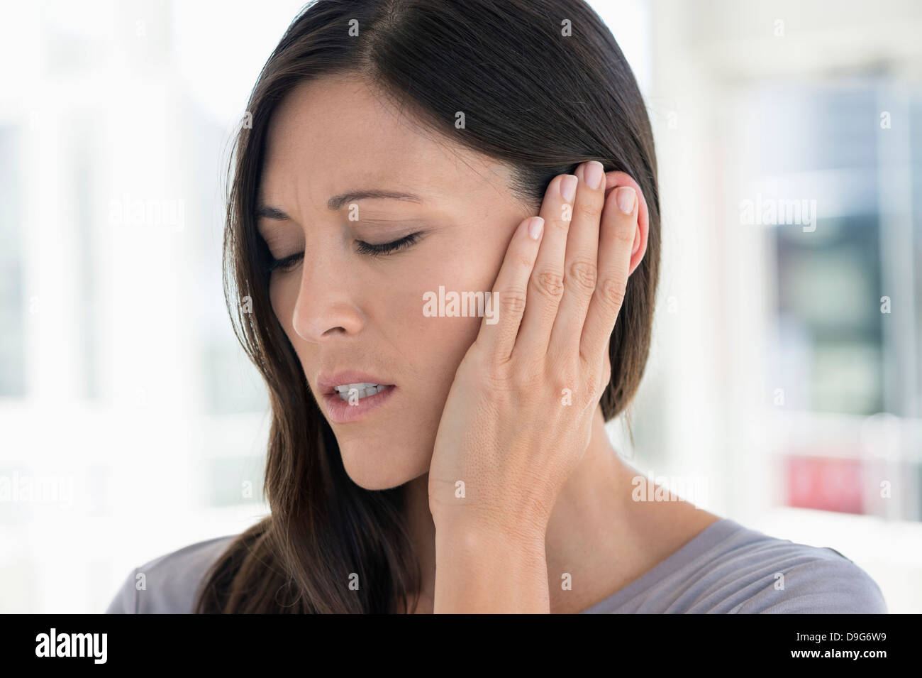 Woman suffering from an ear ache Stock Photo - Alamy