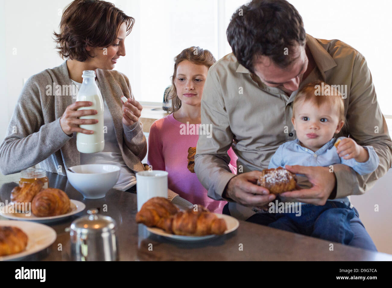 Family having breakfast at a kitchen counter Stock Photo - Alamy