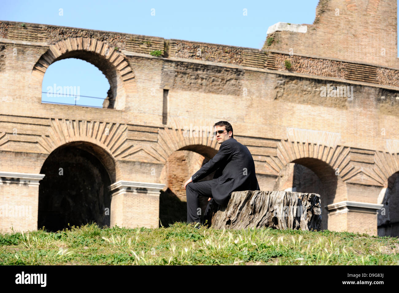 Young man in suit and sunglasses sits by Rome's Coliseum Stock Photo ...