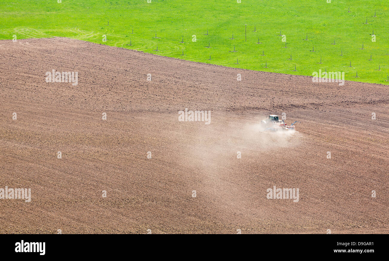Tractor plowing or ploughing field of soil in dry conditions in ...