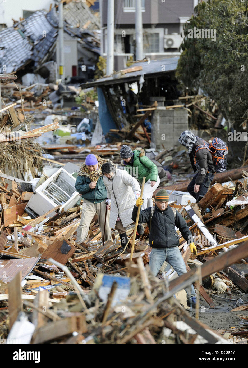 Evacuees walk through the rubble of collapsed houses in Sendai Sendai ...