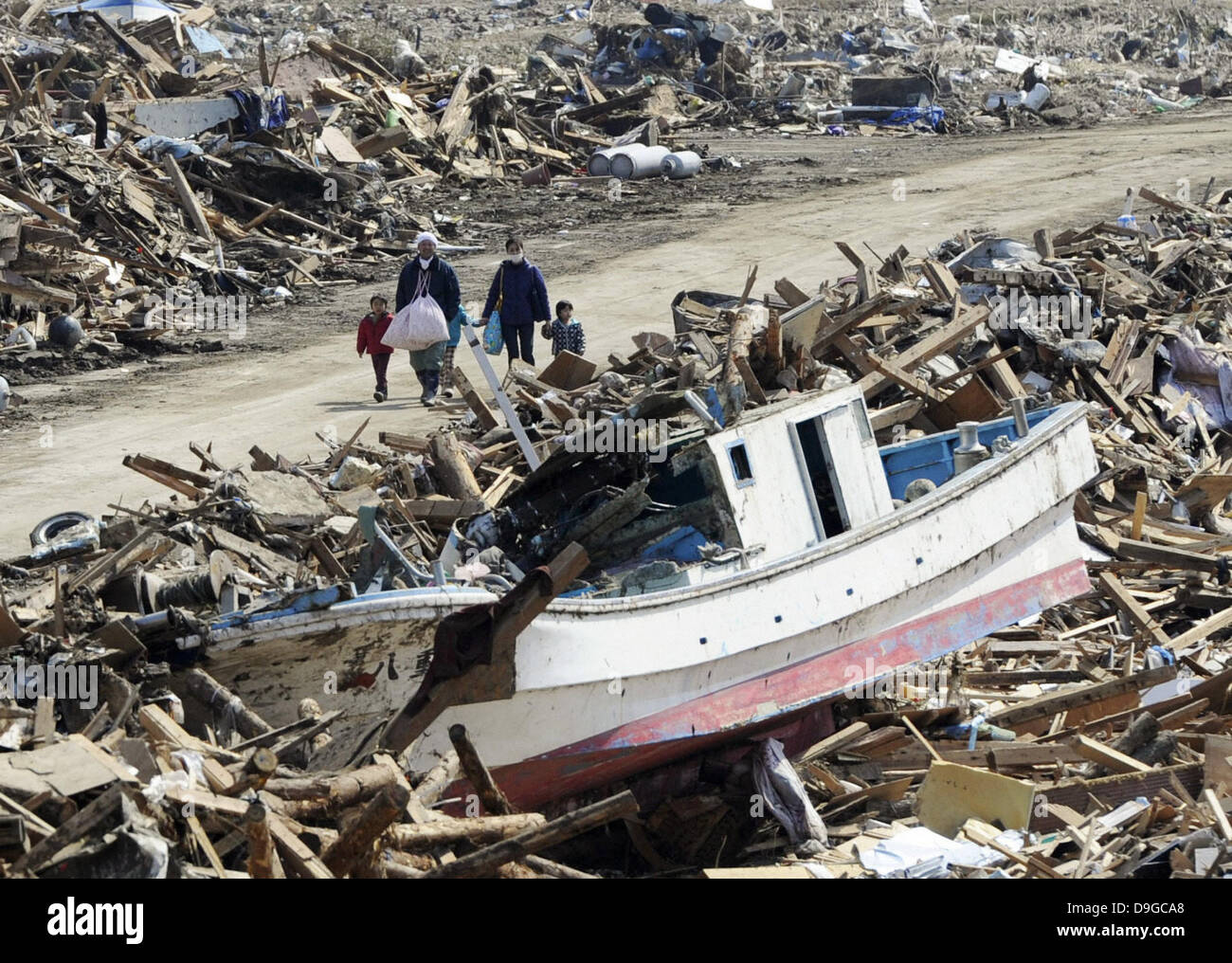 Local residents walk through debris in the town of Minamisanriku ...