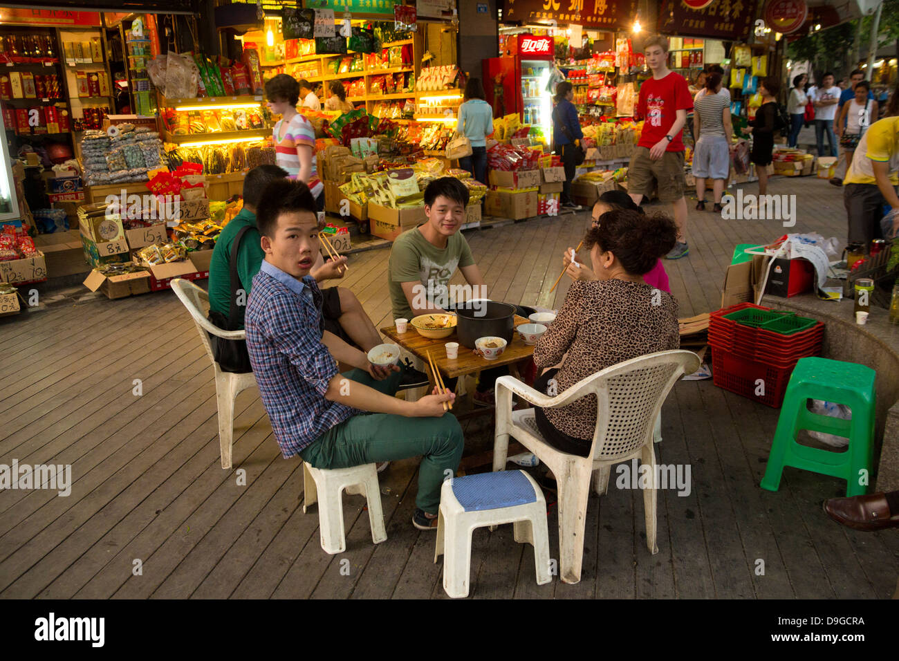 Young friends eating out at a table on the pavement in Chengdu China ...