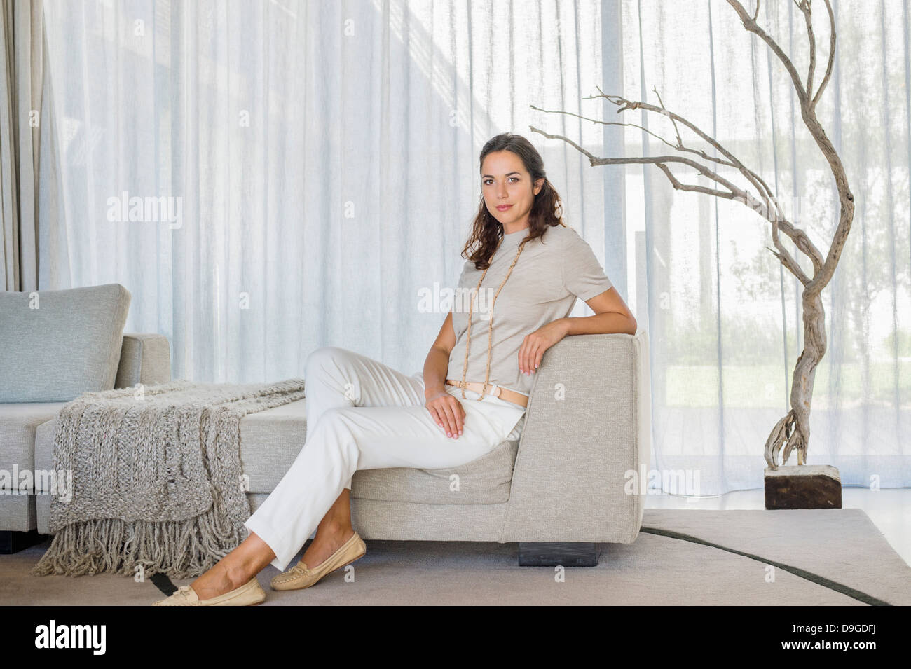 Portrait of a beautiful woman sitting on a couch Stock Photo - Alamy