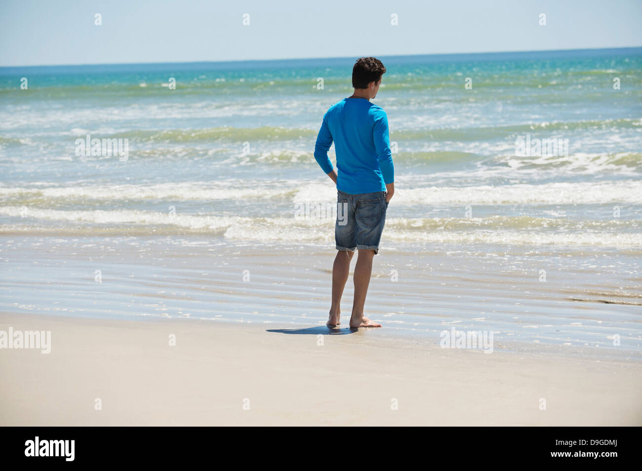 Man standing on the beach and looking at the sea Stock Photo - Alamy