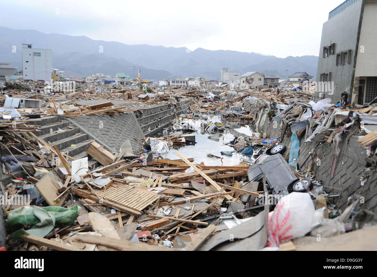Vehicles and debris line a canal in the downtown area of Ofunato, Japan ...