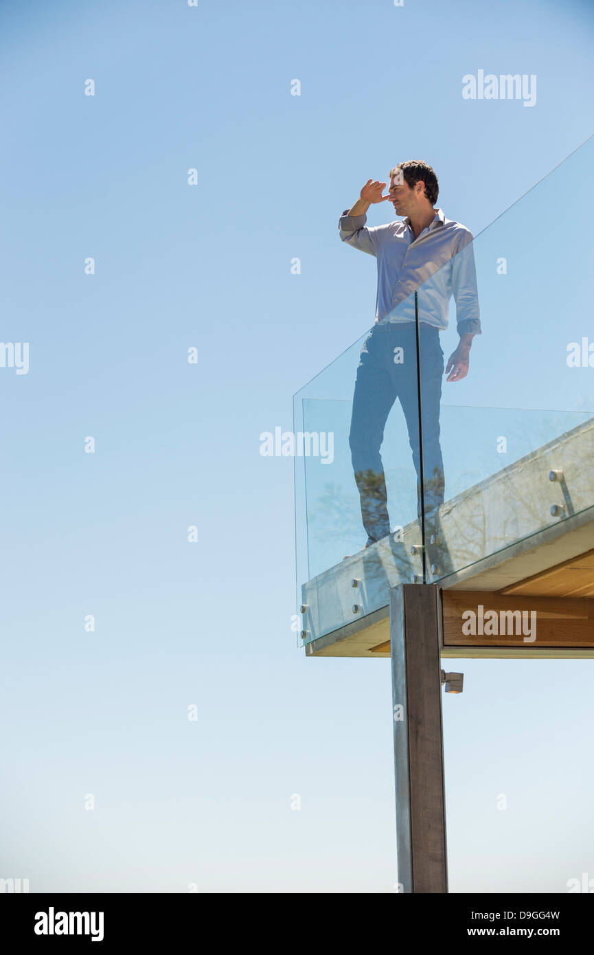 Man standing on the terrace and shielding his eyes Stock Photo - Alamy