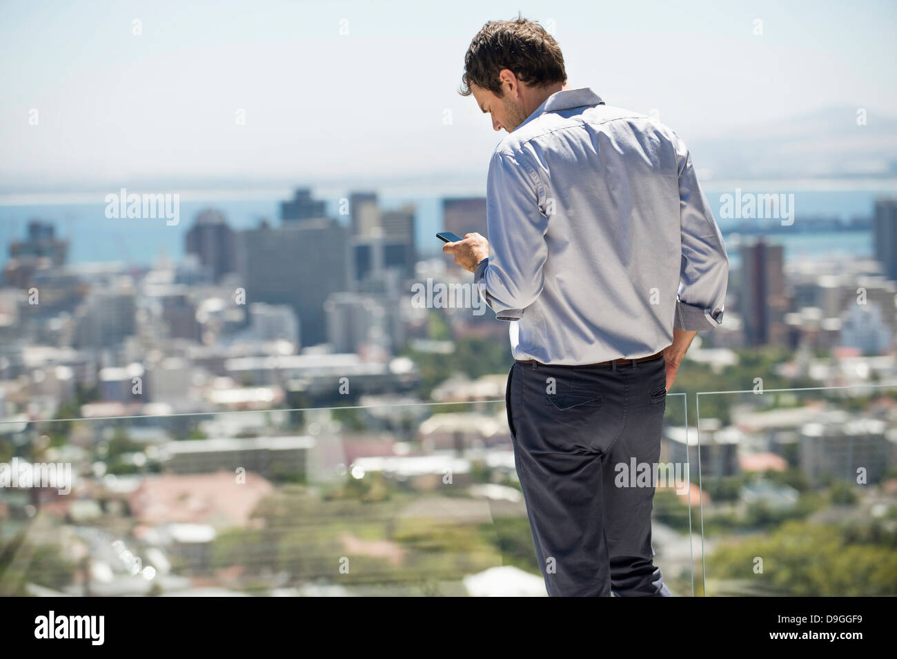 Man standing on the terrace using a mobile phone Stock Photo - Alamy