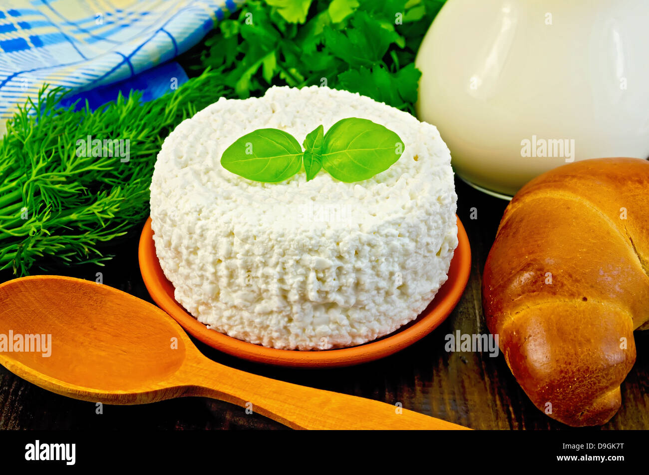 Curd in a clay pot with basil, a wooden spoon, bagel, dill, parsley, a ...
