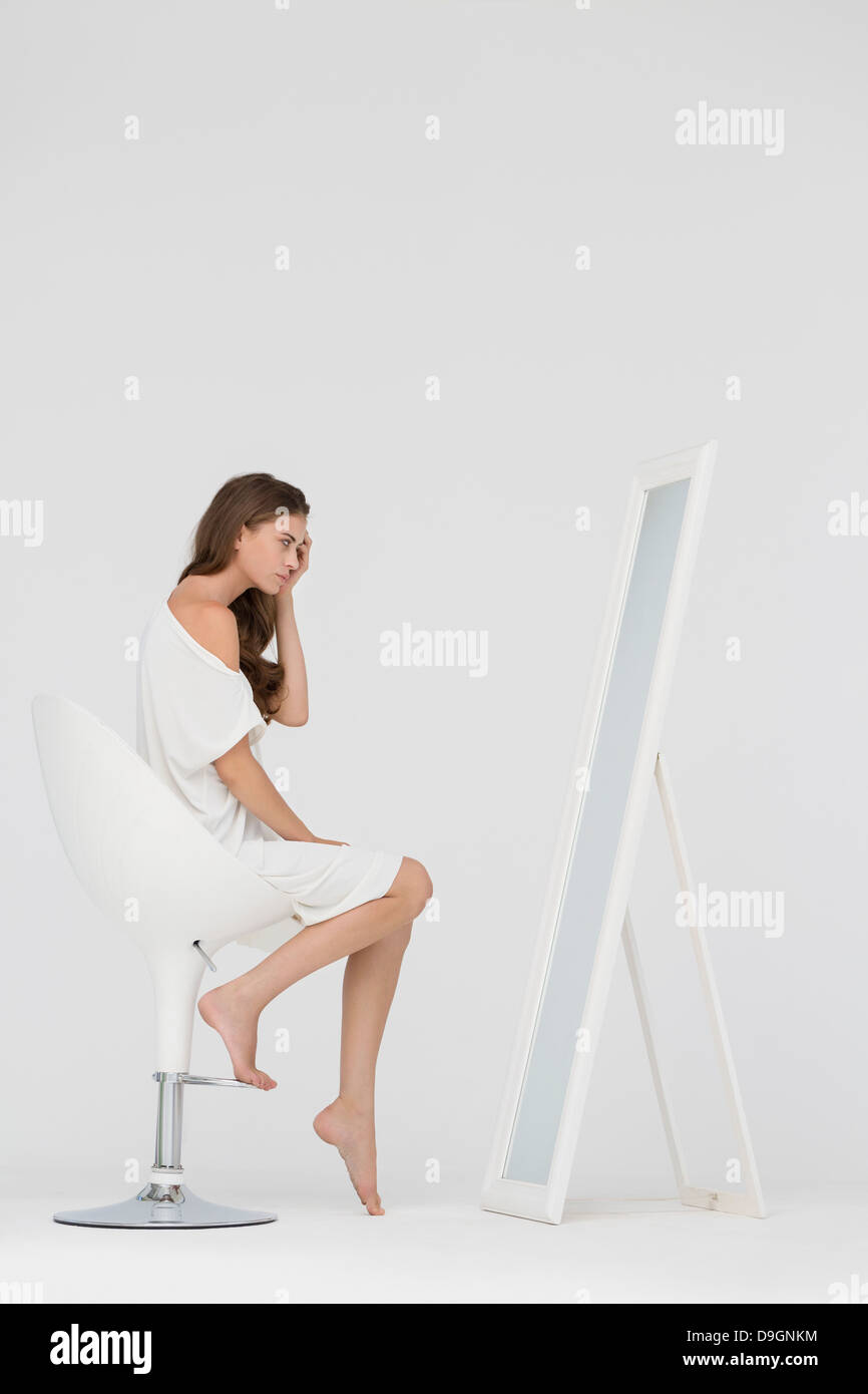 Woman sitting on a chair and looking at mirror Stock Photo - Alamy