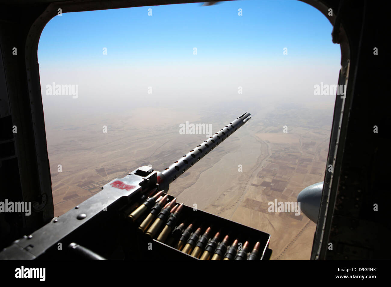A .50 caliber machine gun aims outboard of a CH-53E Super Stallion ...