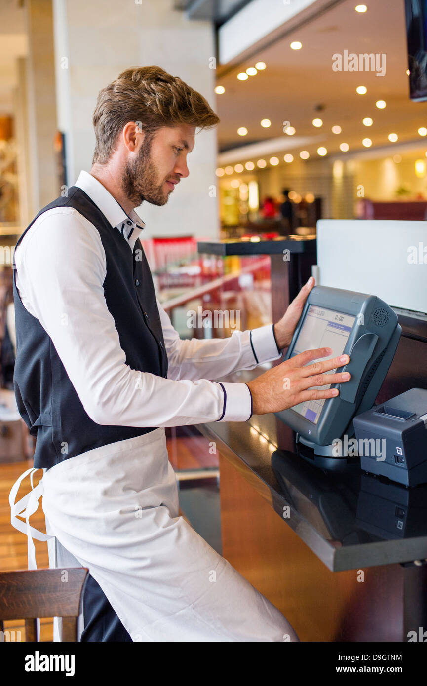 Waiter using a computer at checkout counter in a restaurant Stock Photo ...