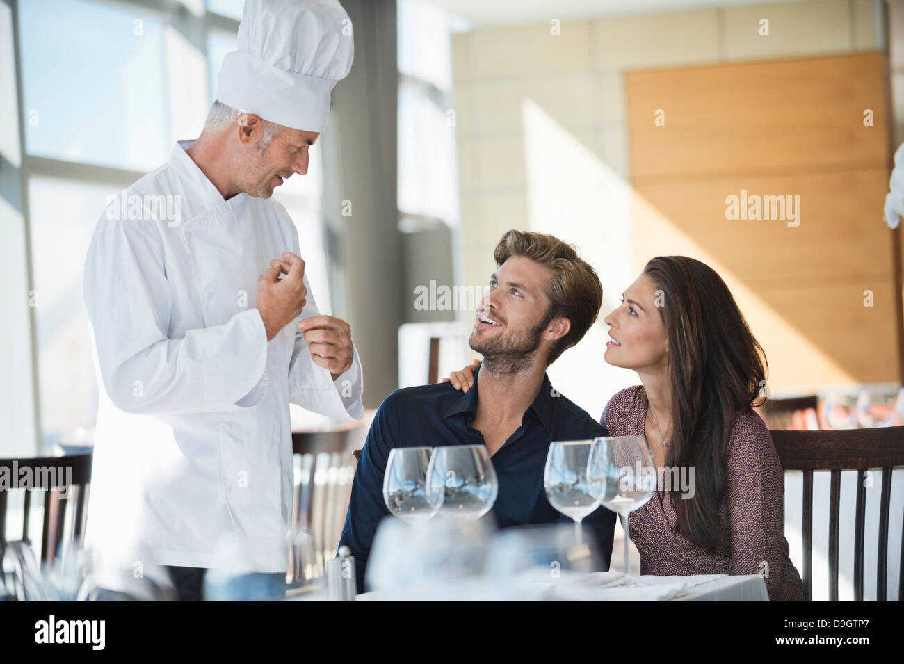 Chef talking to couple at restaurant Stock Photo - Alamy