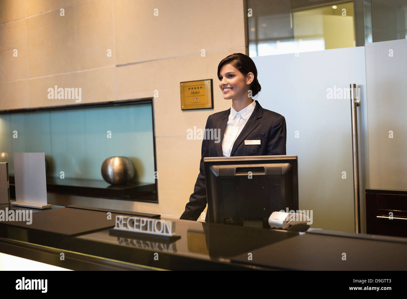 Receptionist standing at the hotel reception counter and smiling Stock ...
