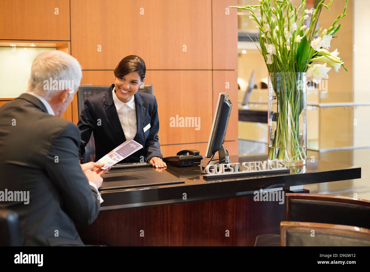 Businessman talking with a receptionist at the hotel reception counter ...