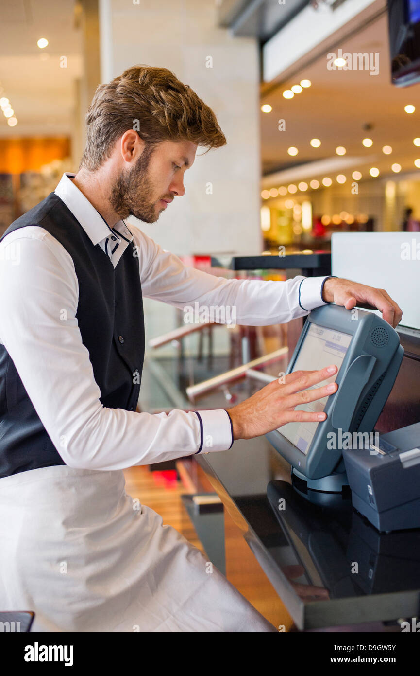 Waiter using a computer at checkout counter in a restaurant Stock Photo ...