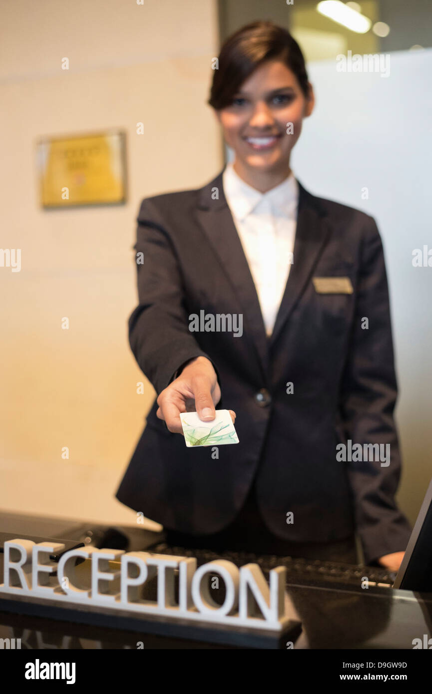 Receptionist holding a key card and smiling at the hotel reception ...