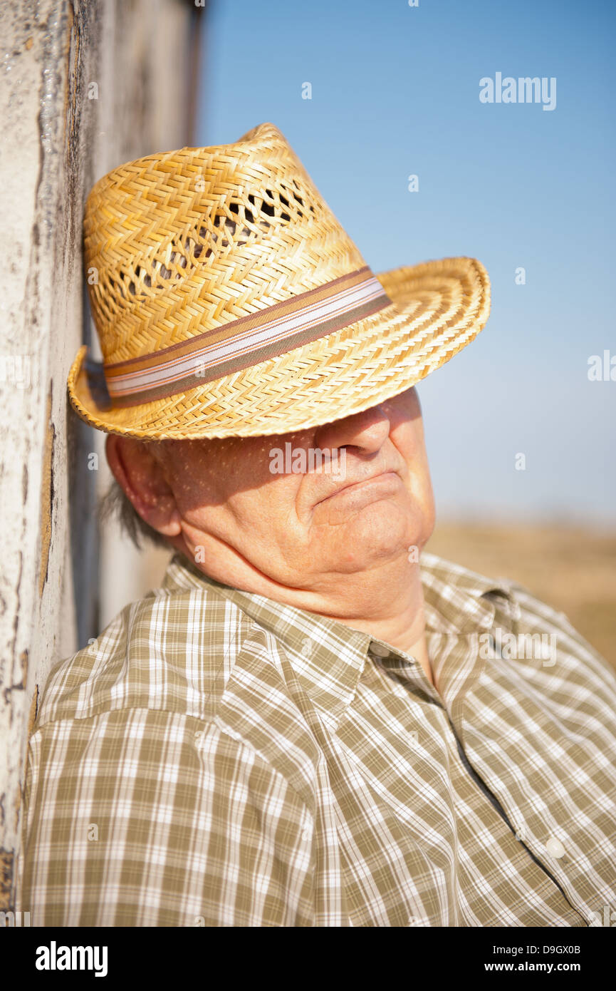 Senior man taking a siesta in the Mediterranean sunshine with his straw ...