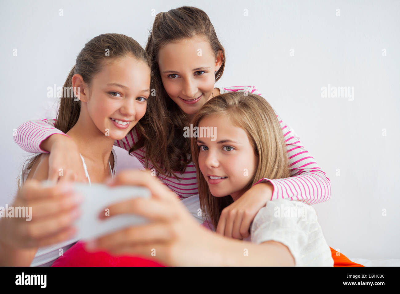 Three girls taking a picture of themselves with a mobile phone at a ...