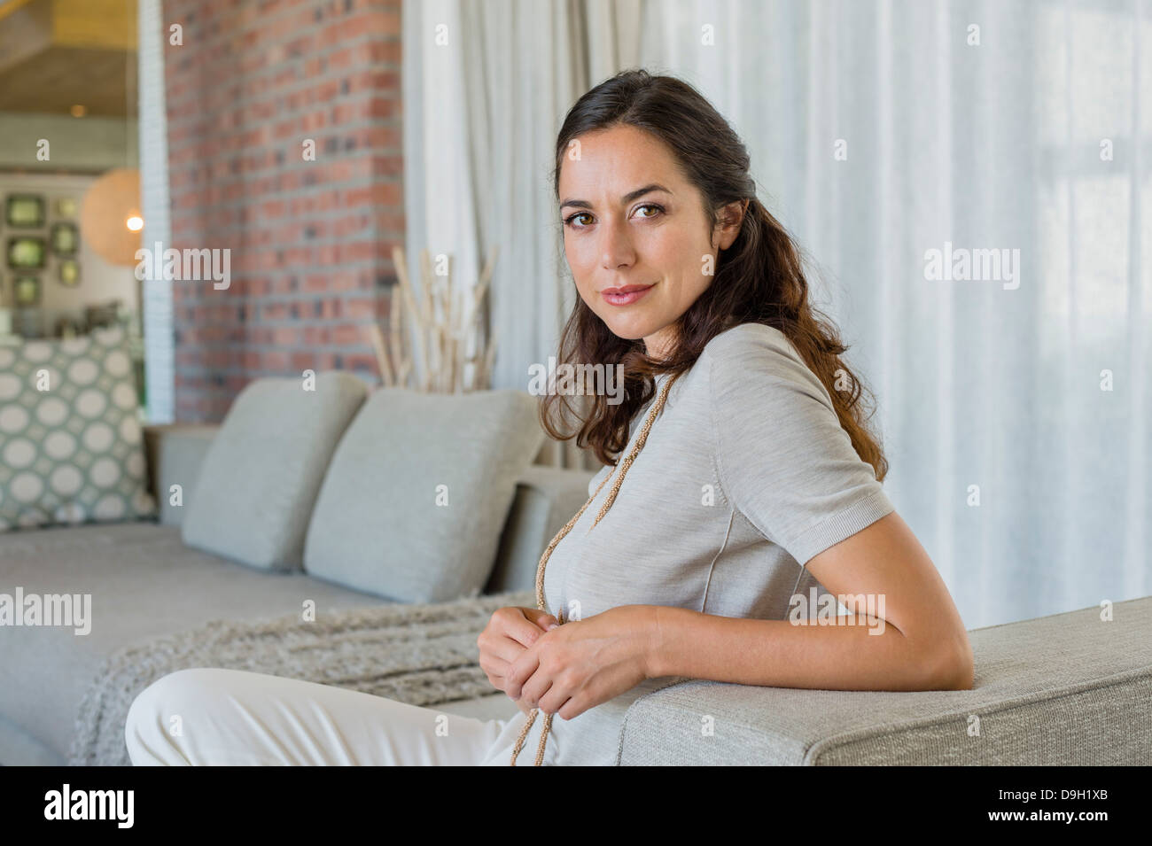 Portrait of a beautiful woman sitting on a couch Stock Photo - Alamy